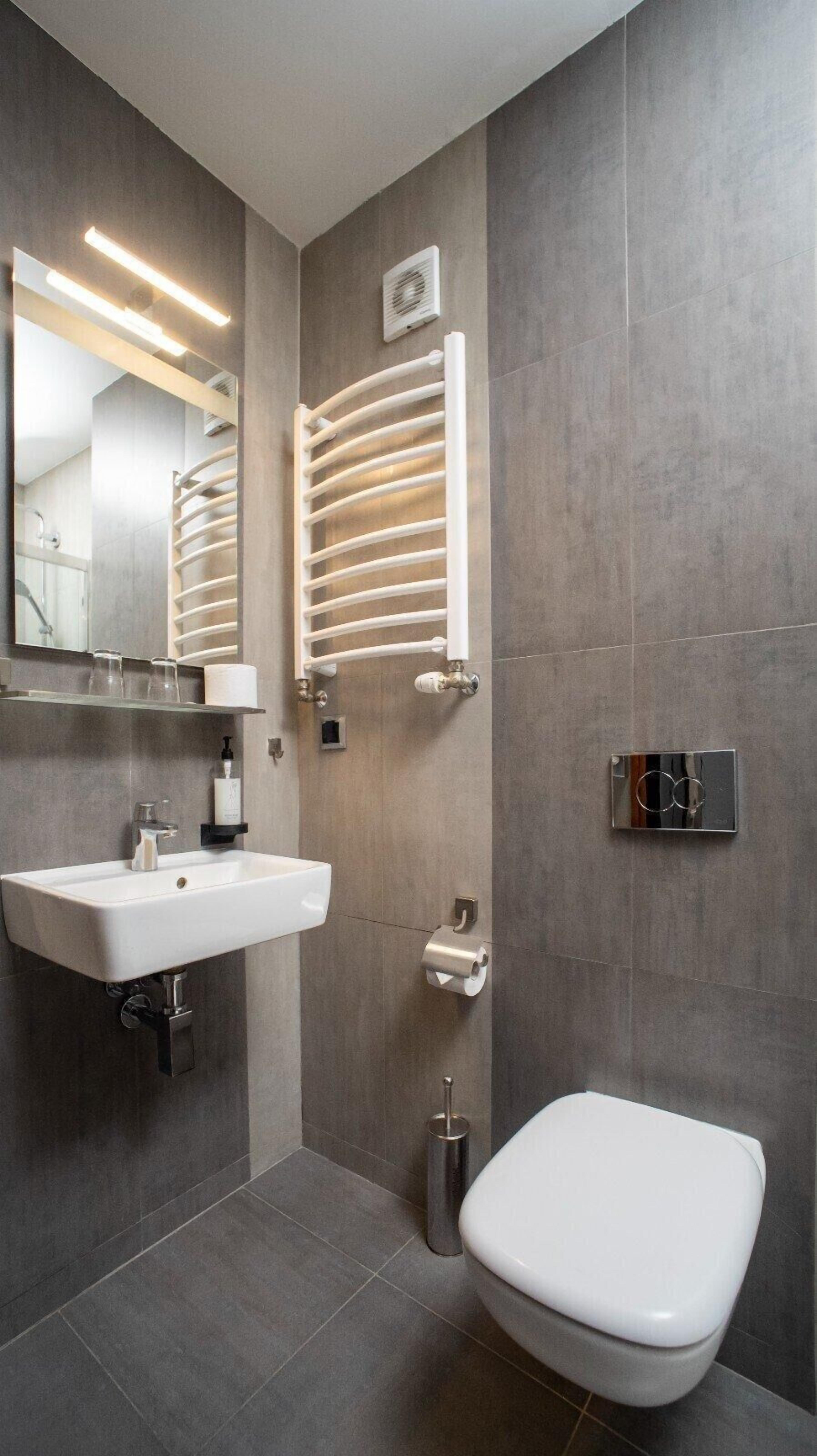 Uma casa de banho moderna com uma sanita, uma pia branca e um porta-toalhas.