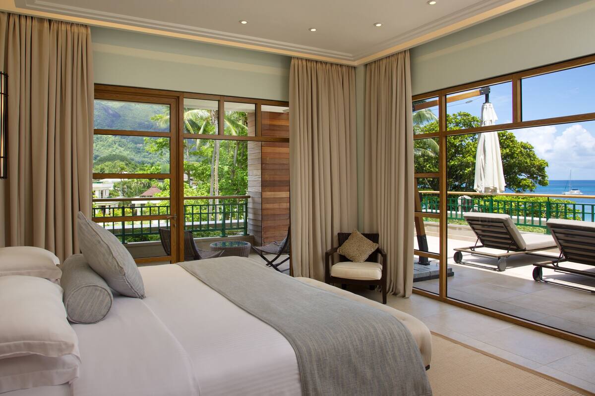 Quarto espaçoso com uma cama grande, varanda com assentos e vista para o oceano.