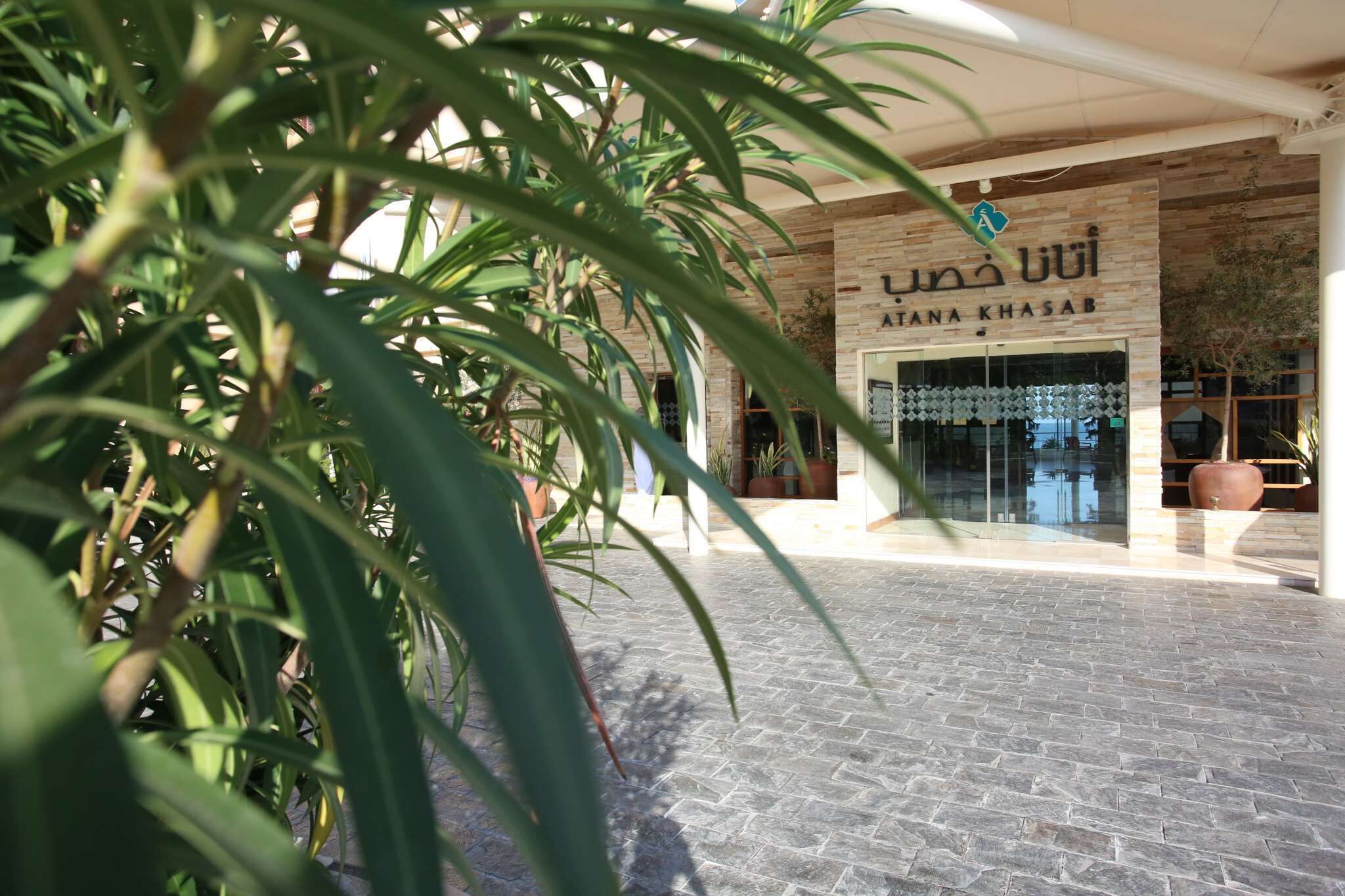 Um edifício com uma placa indicando "Aitana Khasab" e uma entrada de vidro.