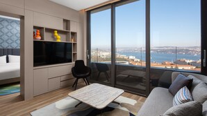 Uma sala de estar moderna com uma grande janela, uma TV de tela plana, um sofá e uma mesa de centro.