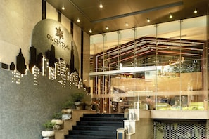 Entrada de hotel com fachada de pedra, uma escadaria e uma janela de vidro que mostra o interior.