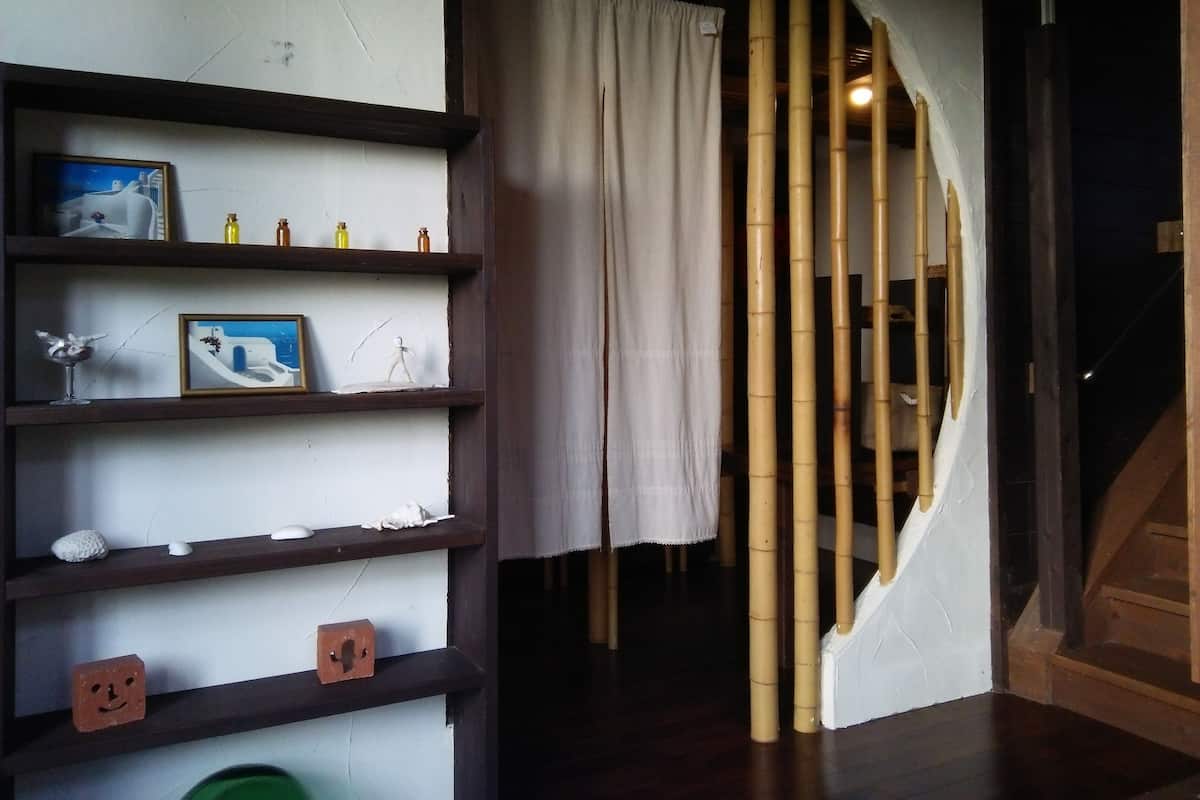 Um quarto com parede branca, prateleiras de madeira e estrutura de bambu.