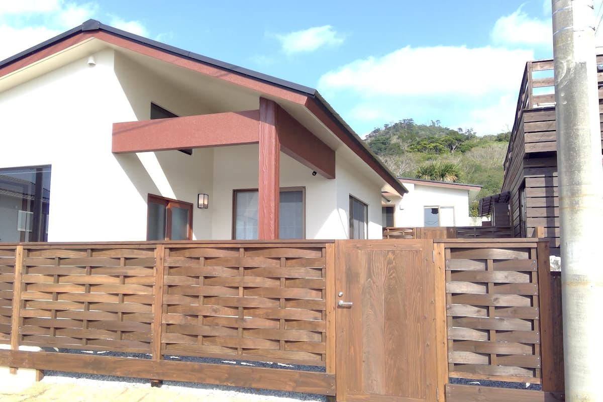Uma casa moderna com telhado inclinado, cerca de madeira e céu limpo.