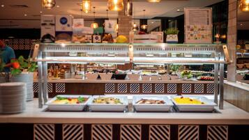 Buffet com diversos alimentos e uma pessoa ao fundo.