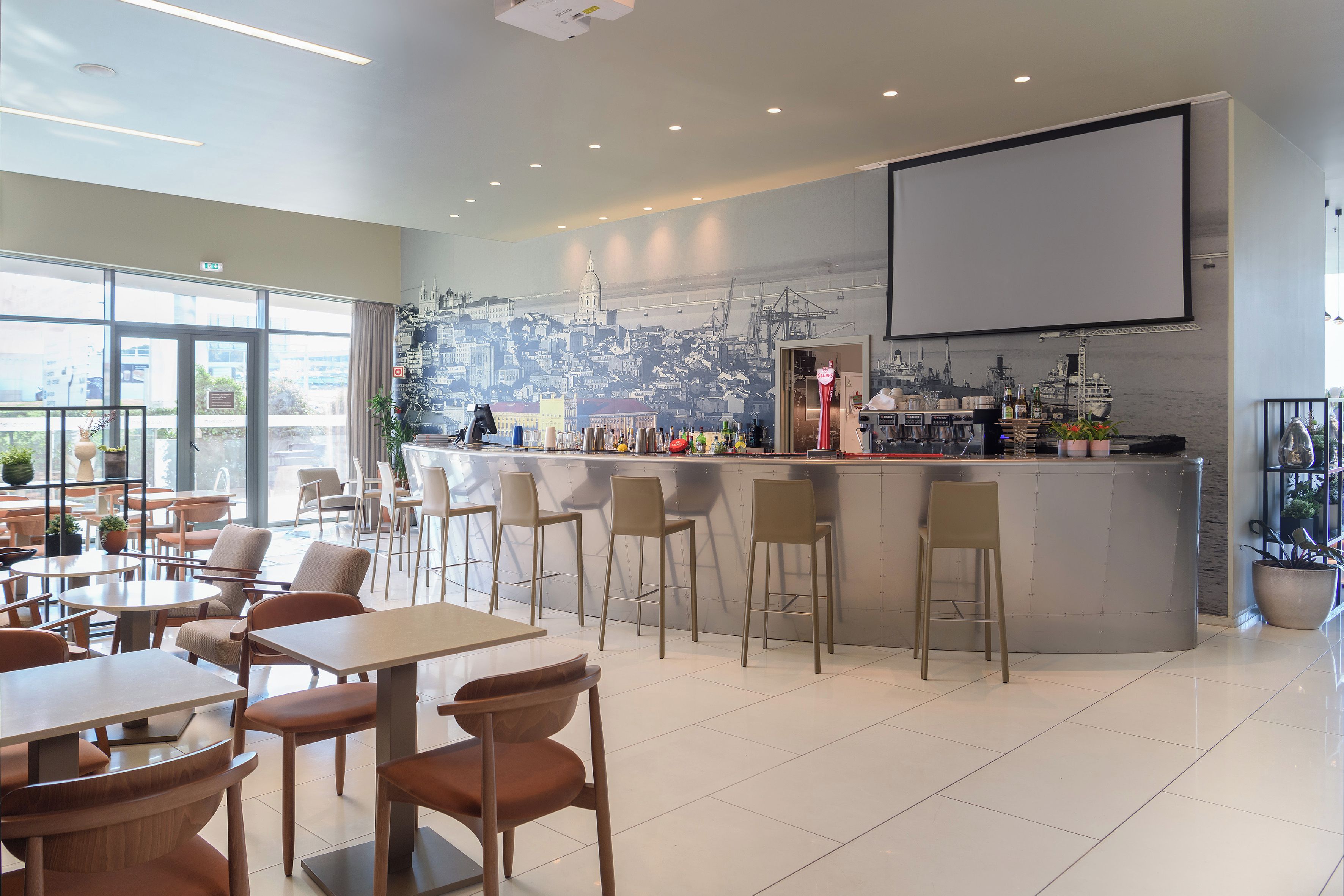 Uma área de bar moderna com um mural de paisagem urbana, banquetas e diversos tipos de garrafas.