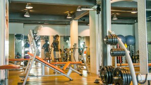 Uma academia com equipamentos de ginástica, espelhos e piso de madeira.
