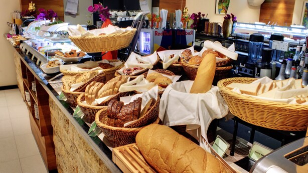 Um buffet com diversos pães e doces dispostos em cestos.