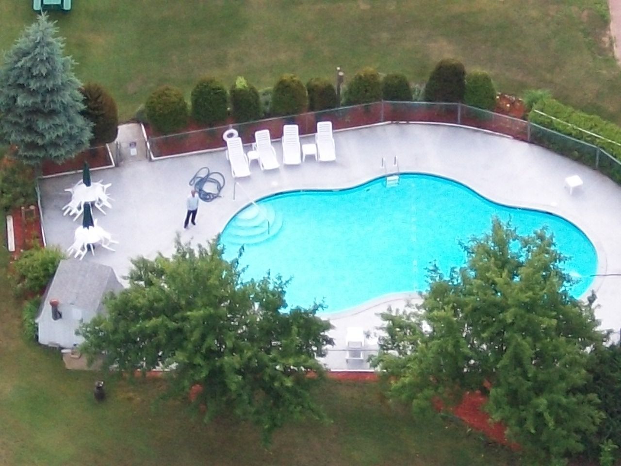 Vista aérea de uma piscina com espreguiçadeiras e uma pequena área de deck.