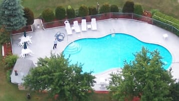 Vista aérea de uma piscina com espreguiçadeiras e uma pequena área de deck.