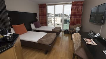 Quarto de hotel com duas camas, uma mesa, uma cadeira, uma televisão e vista para a cidade.