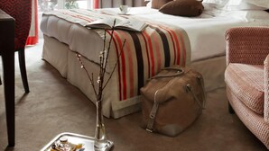 Quarto de hotel com cama, uma cadeira, uma mala e um tabuleiro com comida.