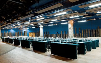 Uma sala de conferências com várias mesas e cadeiras, parede azul com painéis de madeira e um pilar de pedra.
