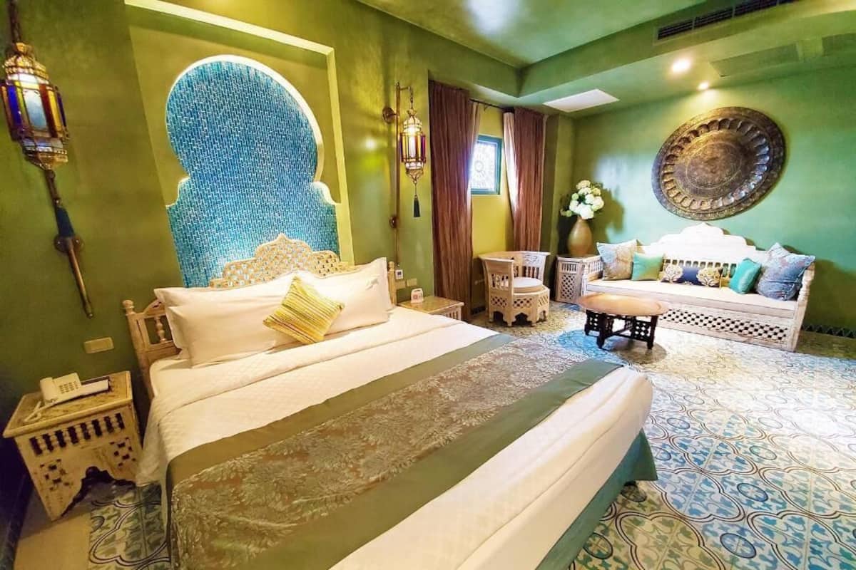 Quarto com uma cama grande, um sofá, uma mesinha e uma parede decorativa.