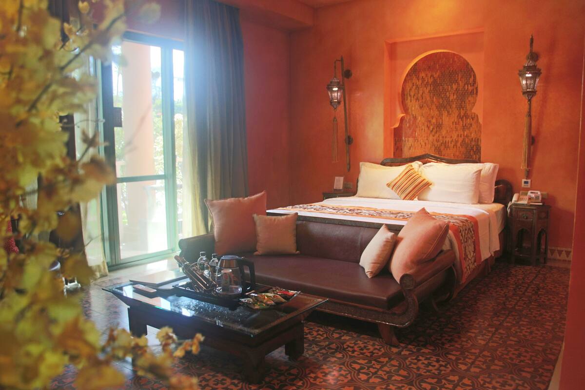 Quarto de hotel com cama, sofá e mesa de centro com bandeja.