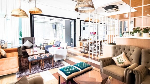 Uma sala de estar moderna com um sofá, poltronas e uma mesa de centro. Há uma janela grande que oferece luz natural e vista para o exterior.