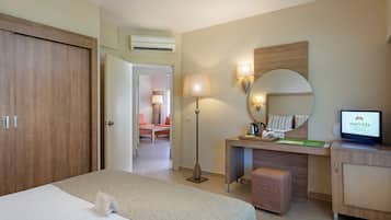 Quarto de hotel com cama, escrivaninha, cadeira, abajur, espelho e televisão.