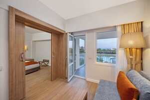 Quarto de hotel moderno com piso de madeira, uma cama, um sofá e uma varanda com vista para a cidade.