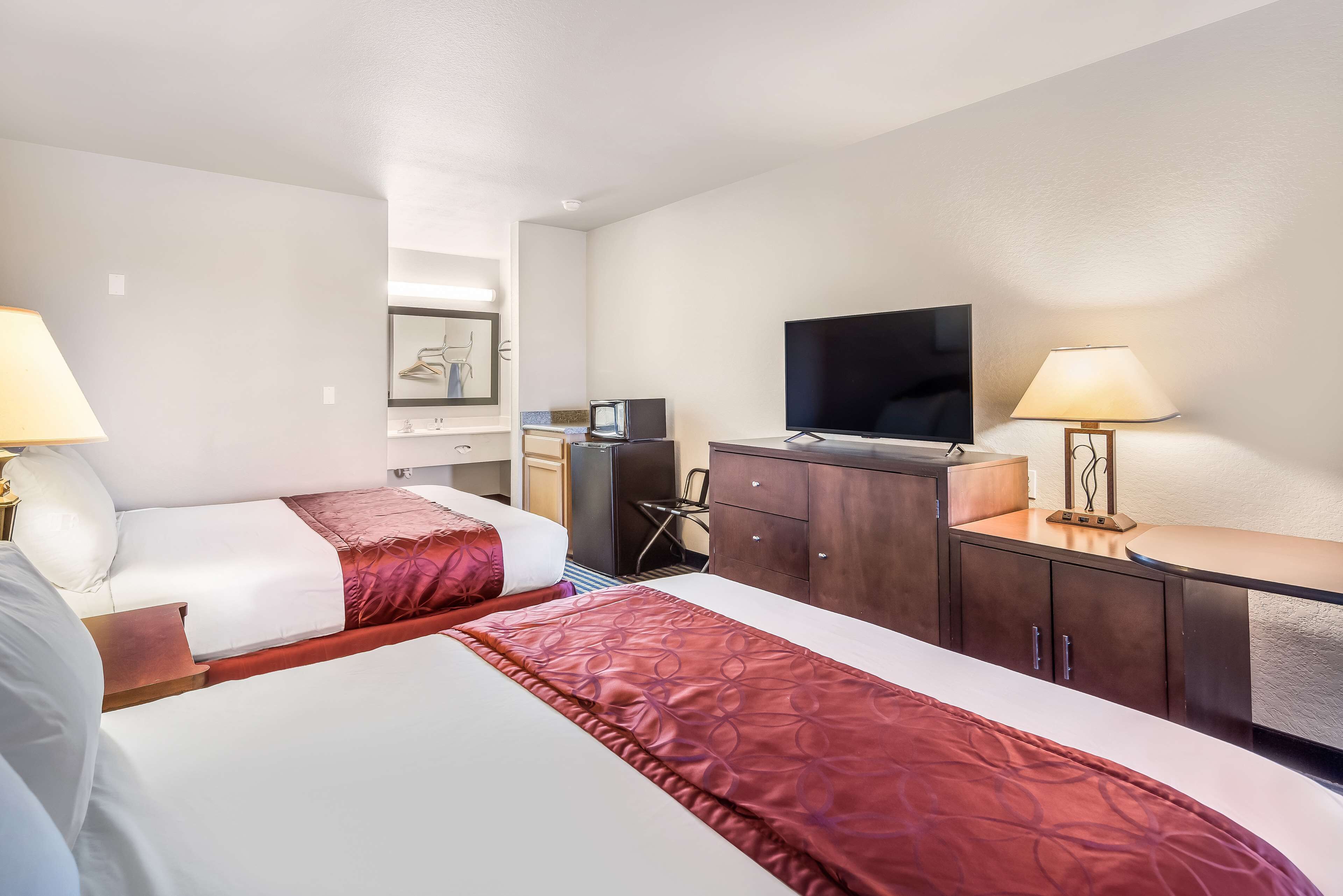 Quarto de hotel com duas camas, televisão, secretária e uma cadeira.