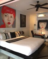 Quarto moderno com uma cama grande, um ventilador de teto e obras de arte nas paredes.