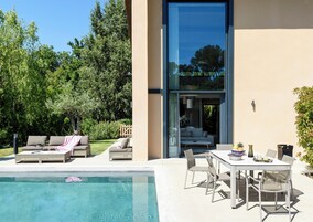 Uma casa moderna com piscina, área de estar externa e porta de vidro que dá para uma sala de estar.