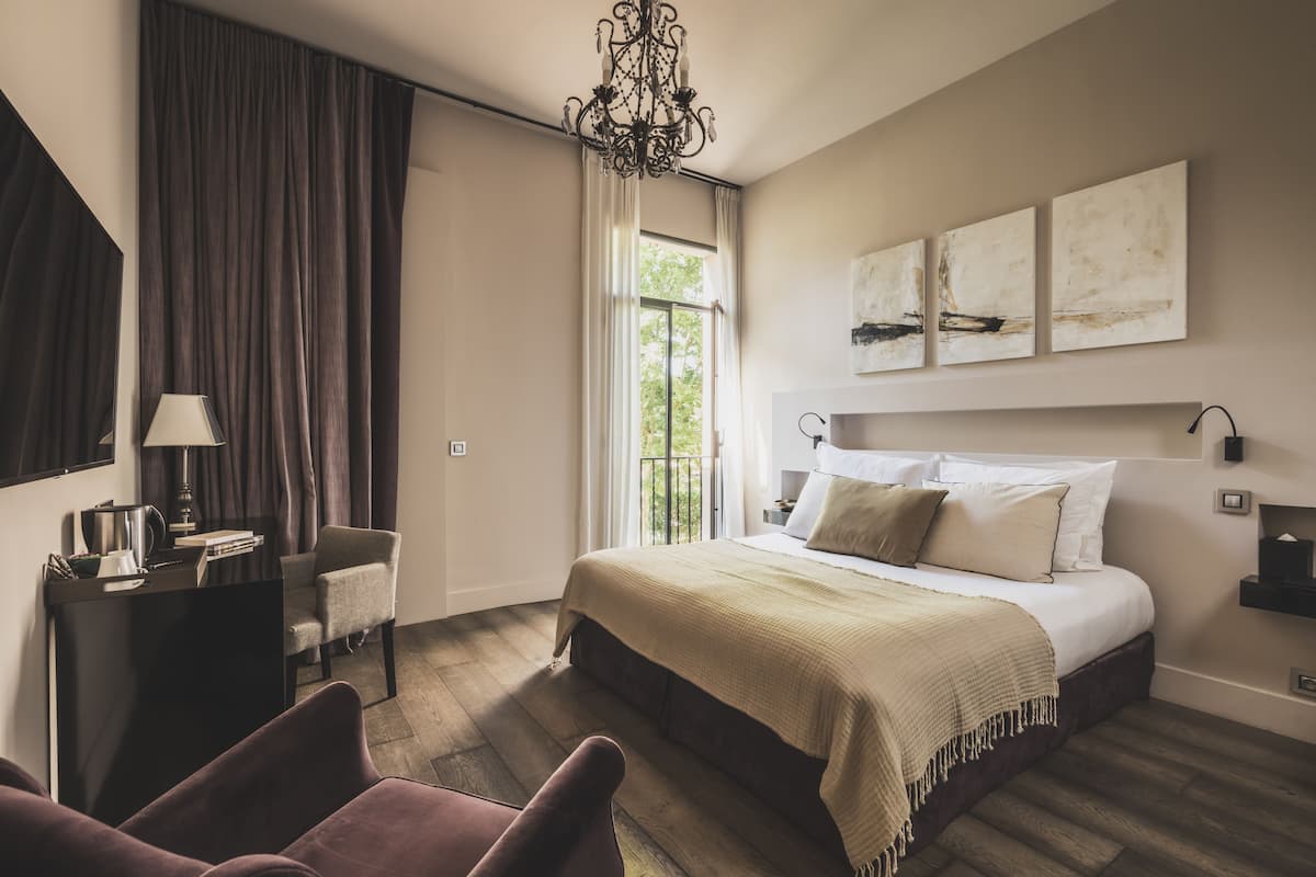 Quarto com uma cama grande, escrivaninha, cadeira e lustre.