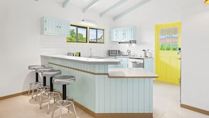 Uma cozinha moderna com ilha central, banquetas e armários azul-claros.