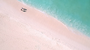 Vista aérea de uma praia com águas turquesa cristalinas e uma faixa de areia.
