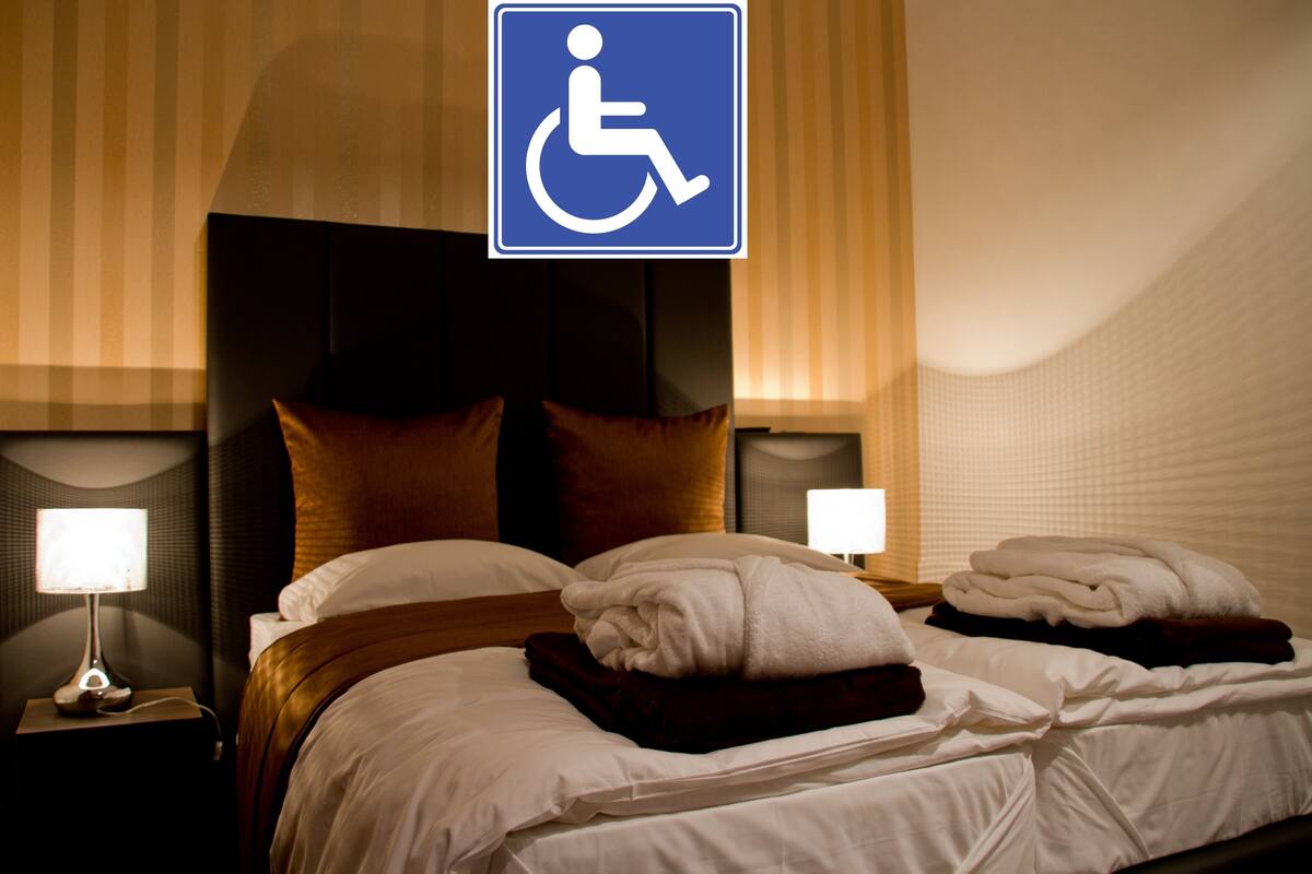 Quarto de hotel com uma cama grande, duas mesas de cabeceira e um sinal de acessibilidade para cadeiras de rodas.
