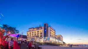 Um hotel com vários andares, área de estar ao ar livre e vista para a praia.