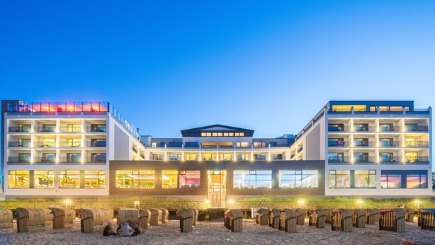 Hotel com vários andares, um átrio central, grandes janelas e um andar térreo com piso de areia.