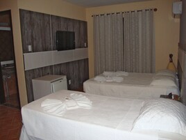 Quarto de hotel com duas camas, uma escrivaninha pequena e uma televisão na parede.