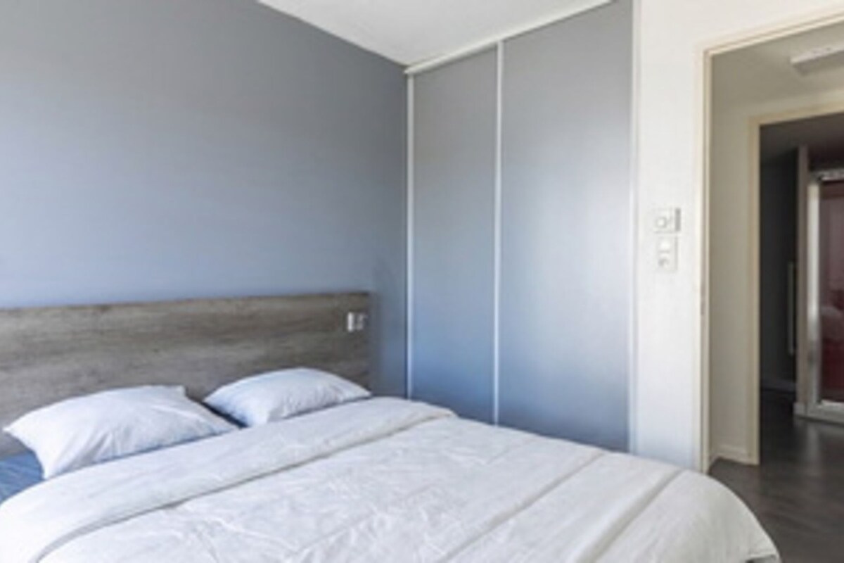 Um quarto com uma cama, um guarda-roupa e uma porta que dá para outro cômodo.