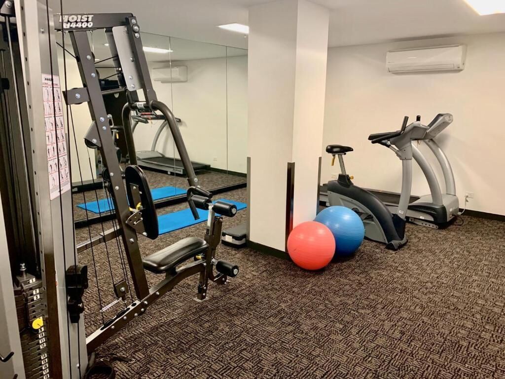 Uma academia com equipamentos de ginástica, esteira e bolas de exercícios.