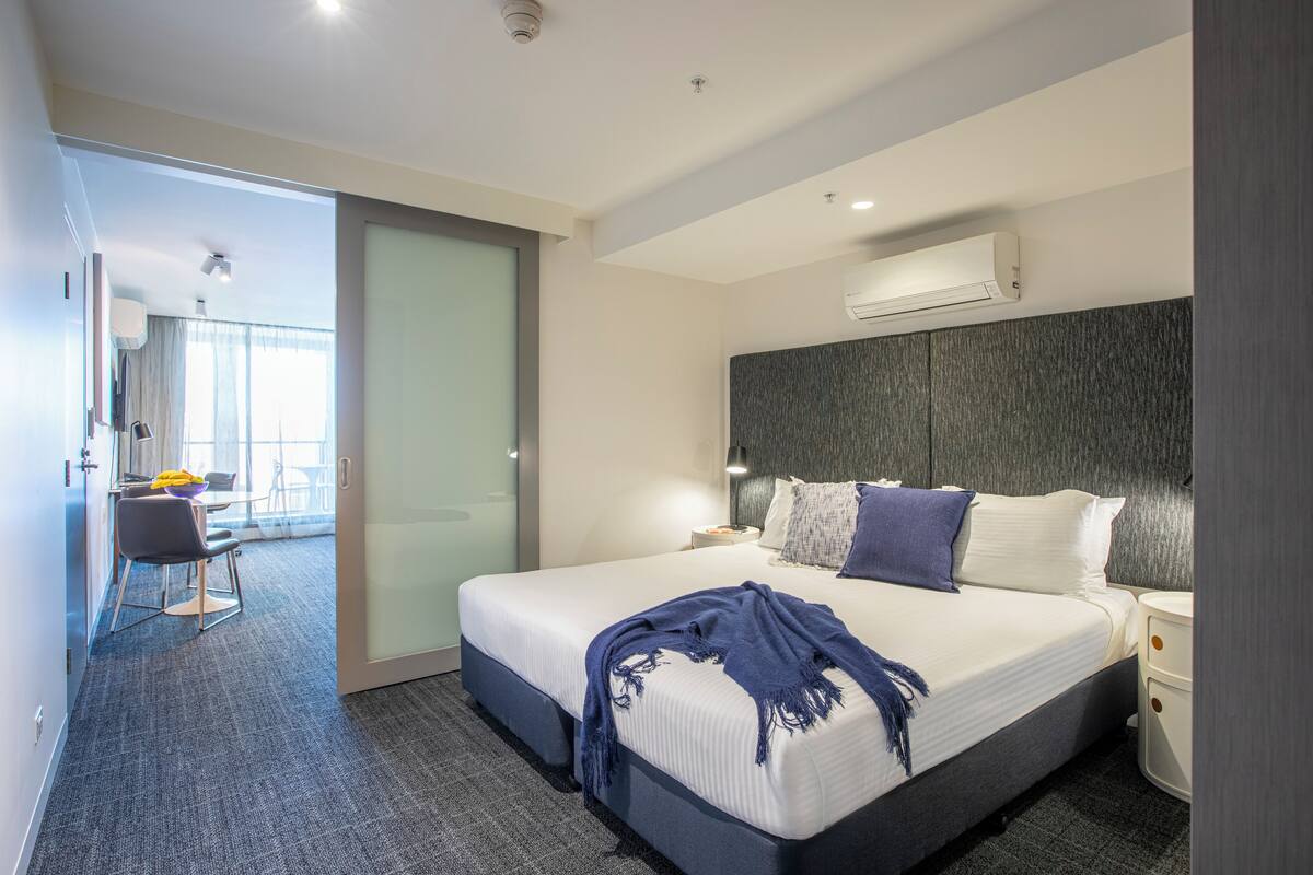Quarto de hotel moderno com uma cama grande, uma escrivaninha com cadeira e vista para o exterior.