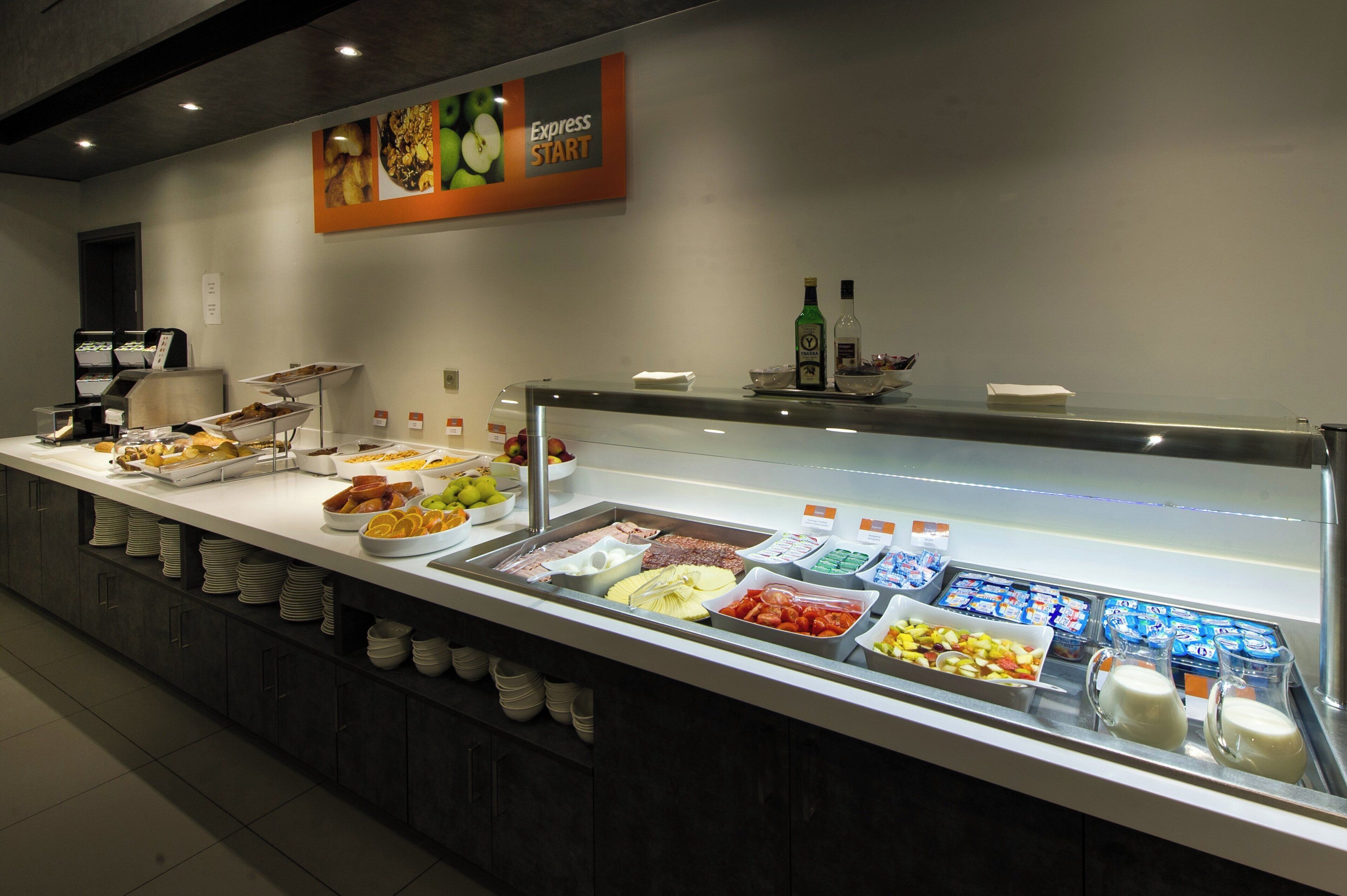 Uma área de buffet com diversos alimentos e uma vitrine de vidro.