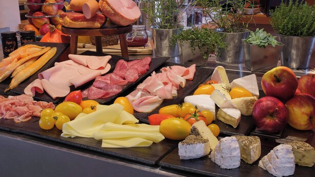 Exposição de queijos, carnes e frutas.
