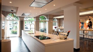 Uma cozinha moderna com ilha central, janelas amplas e área de jantar com cadeiras.