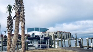 Um imóvel à beira-mar com um deck coberto, um edifício com várias sacadas e um píer que se estende sobre a água.