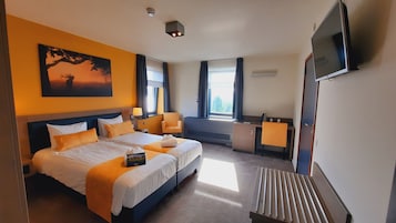 Quarto de hotel com uma cama grande, uma escrivaninha, uma cadeira, uma televisão e um quadro na parede.