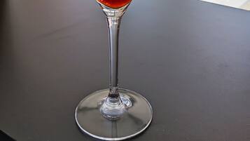Um copo de martini com líquido escuro sobre uma mesa dentro de um café.