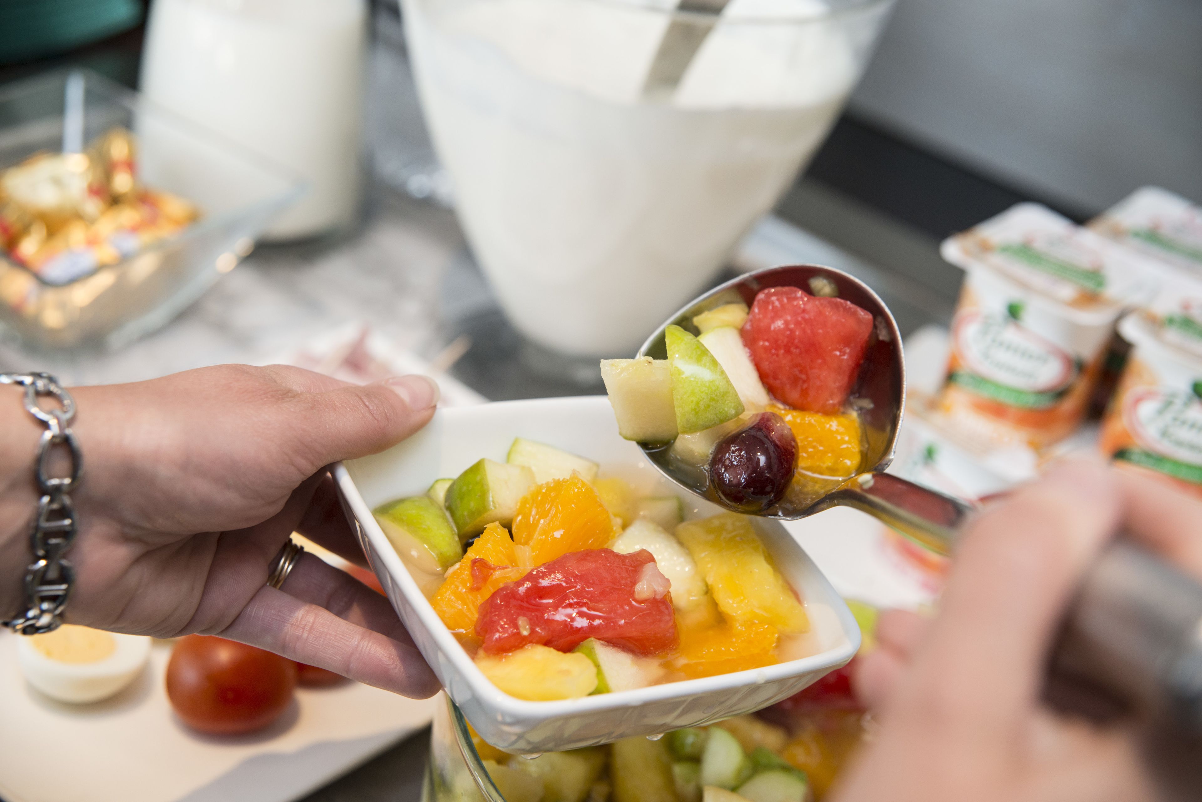 Uma pessoa segurando uma tigela de salada de frutas com uma colher.