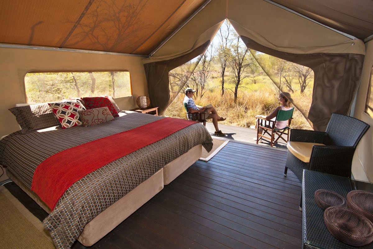 Acomodação em tenda com cama, um espaço para leitura e vista para o exterior.