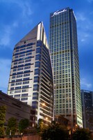 Dois edifícios altos com fachadas de vidro refletivo e céu claro.