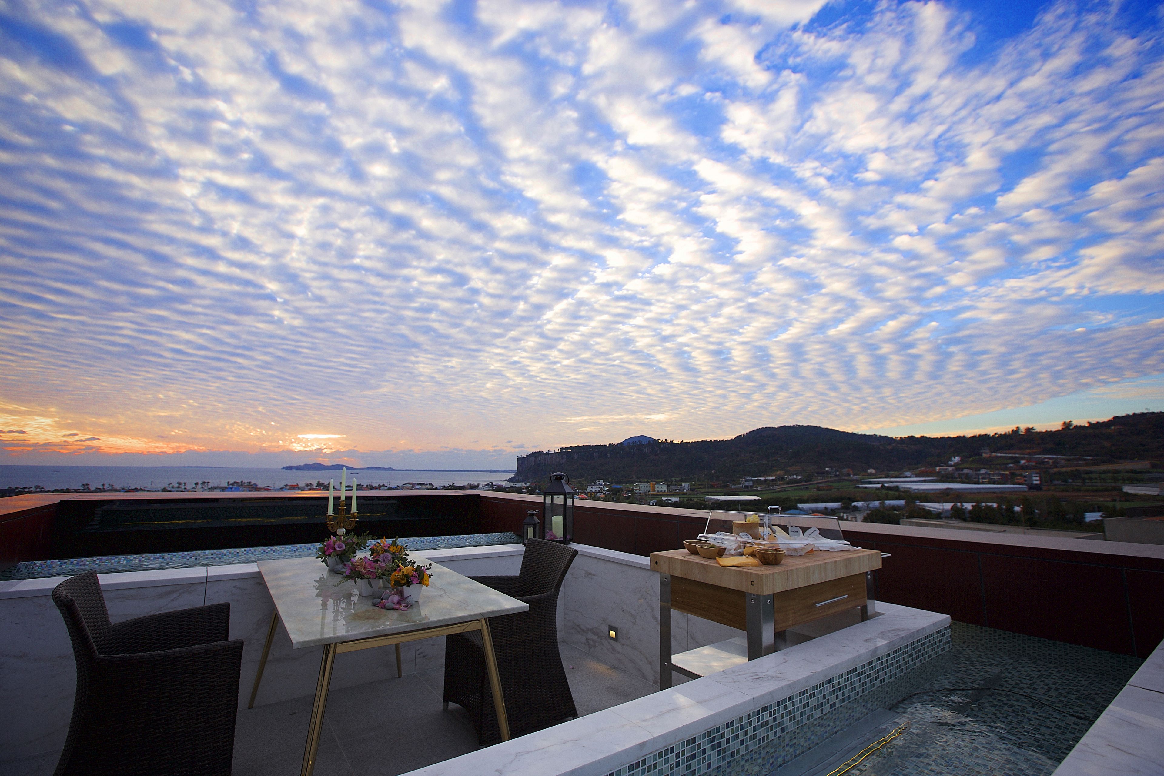 Terraço no telhado com mesa de jantar, cadeiras e uma pequena piscina.