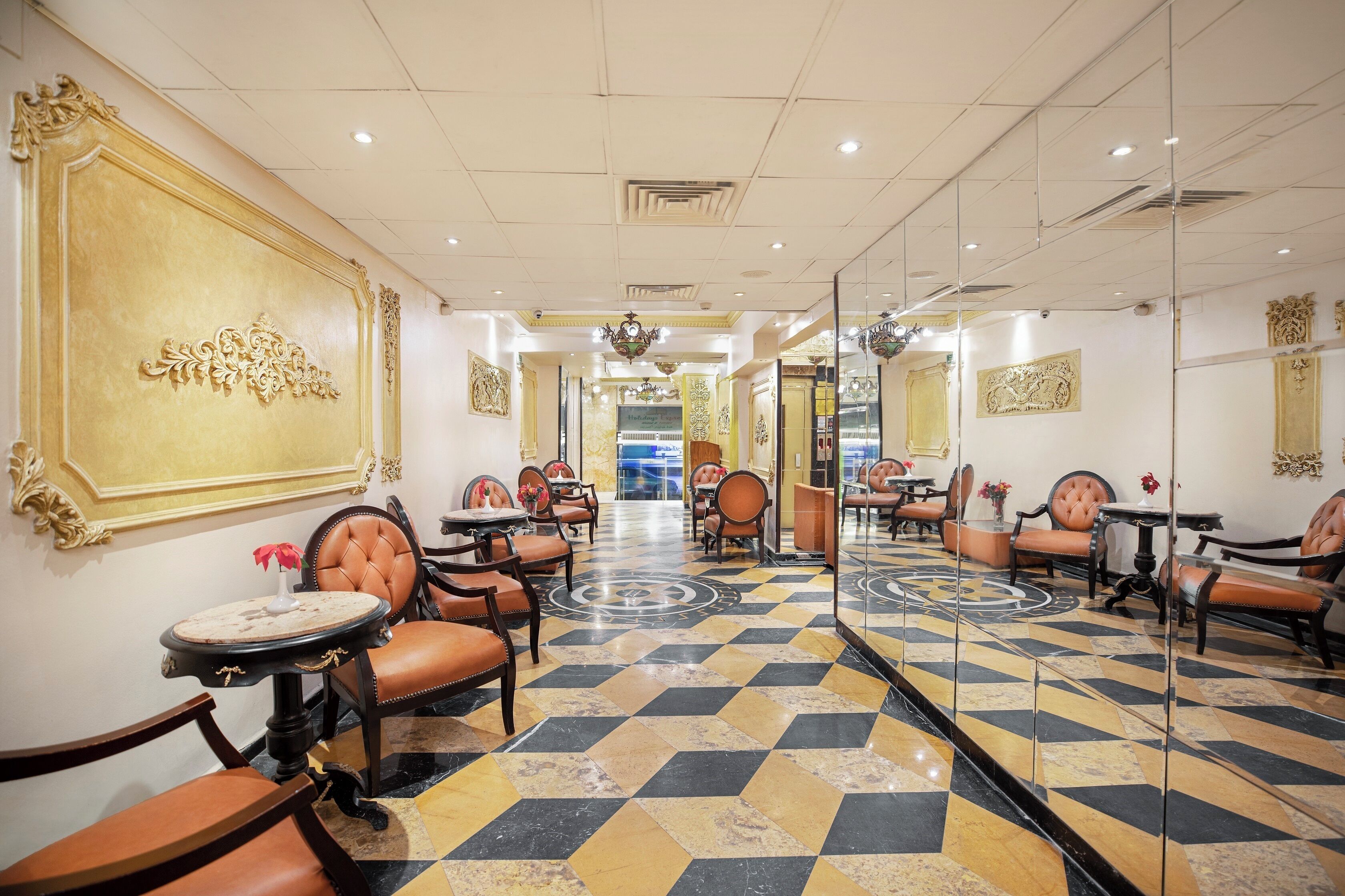 Um hall de hotel com piso xadrez, paredes espelhadas e decoração de parede elaborada.