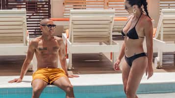 Uma área de piscina com espreguiçadeiras e palmeiras.
