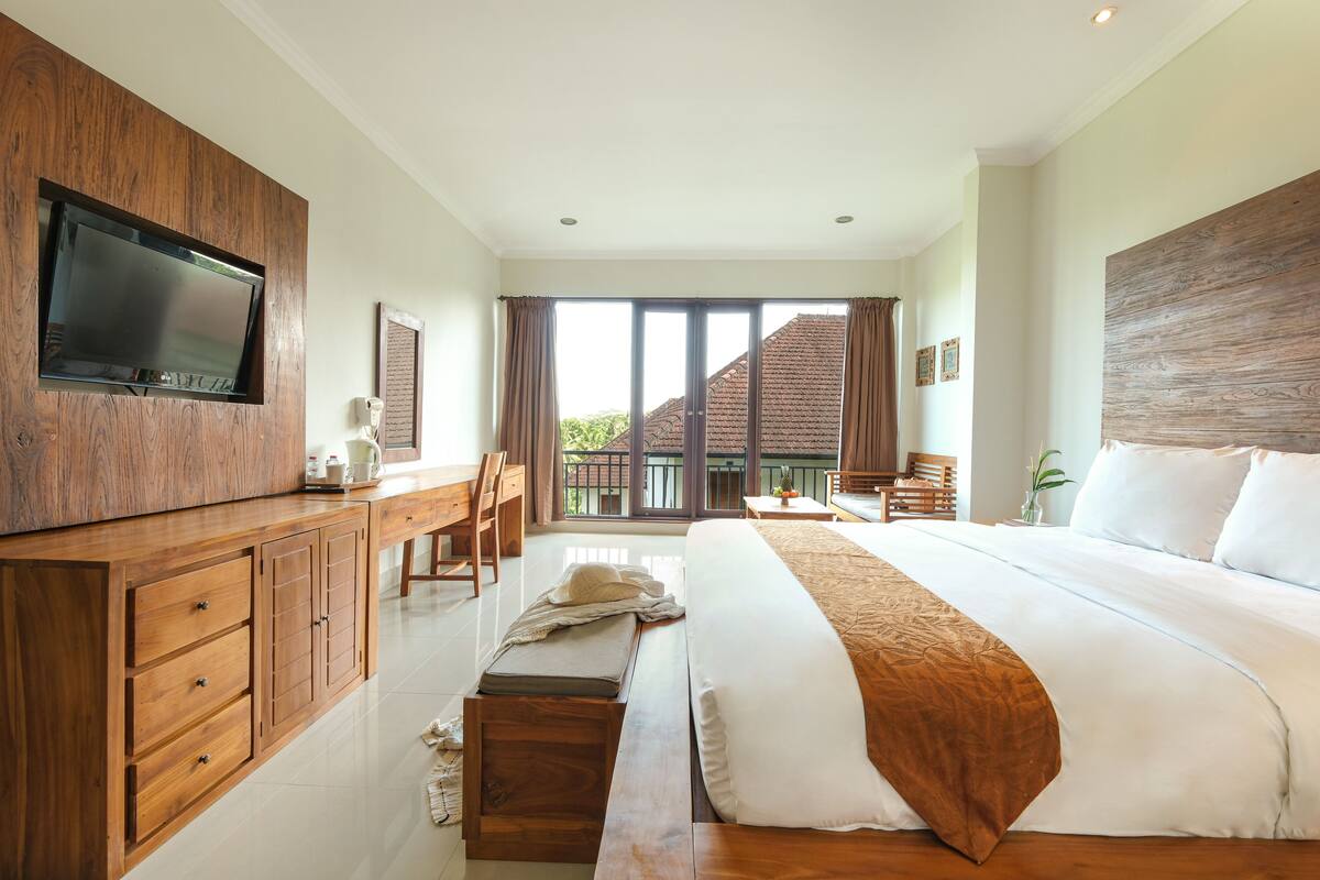 Um quarto espaçoso com uma cama grande, móveis de madeira, televisão e uma varanda com vista.