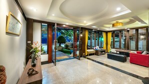 Um hall de hotel moderno com balcão de recepção, área de estar e grandes janelas.