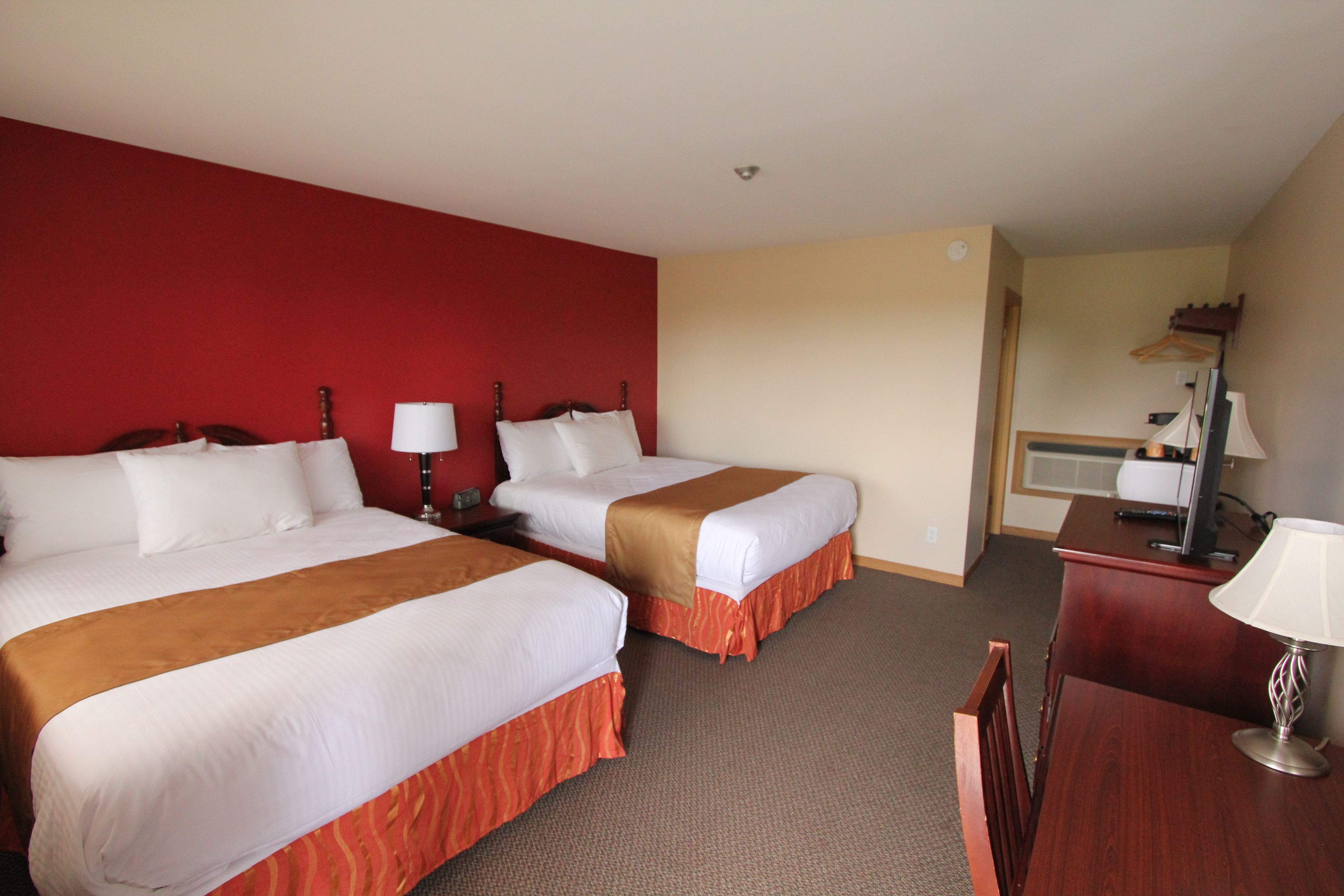 Quarto de hotel com duas camas, uma escrivaninha e uma cadeira.