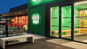 Um edifício moderno com um destaque para a placa 'Grillen', portas de vidro e o logotipo 'IKEA' visível.